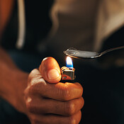 Hands, spoon and man with drugs, flame and heroin with meth, addiction ...