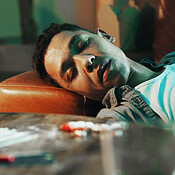 Drugs, overdose and man on sofa in dark with pills, health risk and ...