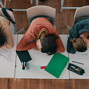 Tired, sleeping and students on desk in classroom at school with ...
