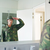 Man, soldier and mirror in bathroom, home and salute with uniform, sign ...