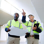 Construction, pointing and men with blueprint in building for ...