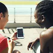 Runner, phone and reading with friends in stadium for training schedule ...