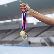 Sport, winner and hands of runner with medals at stadium for track ...