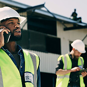 Phone call, architect and man by warehouse for maintenance, talk and building. Mobile ...