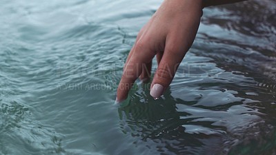 Hands, water and nature with the hand of a woman touching the ocean or ...