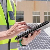 Tablet data, solar panel app and roof construction worker working on ...