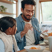 Father, kids and a girl eating spaghetti with her family in the dining ...