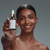Woman, serum bottle and face in studio for shine, health and wellness ...