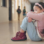 Scared, loney and a child in a school corridor for bullying, autism or ...