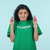 Volunteer, fingers crossed and portrait of a woman in studio for wish ...