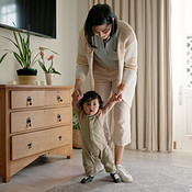 Baby, learning to walk and support from mama in bedroom of family home ...
