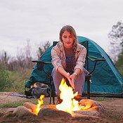 Fire, woman and camping wood with flames for heating hands and calm in ...