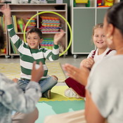 Boy, waving hands and play in classroom, energy and friends at school ...