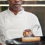 Black man, chef and cooking food in kitchen with pan on fire, speed and ...