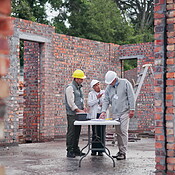 Construction site, team and plan at table for talk, brainstorming and ...