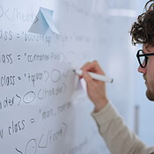 Man, coding and writing on whiteboard in office for review, system ...