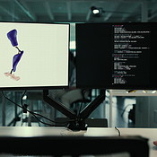 Computer screen, code and programming at desk in laboratory, machine learning and prosthetic ...