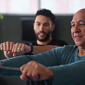 Senior man, resistance band and exercise with coach in gym for strength ...