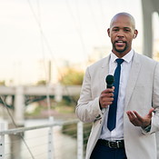 Man, news reporter and smile with microphone in street, face and urban ...