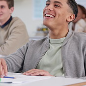 Education, laughing and student man at desk in classroom for lecture ...