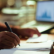 Hands, computer and businessman writing in notebook for trading details ...